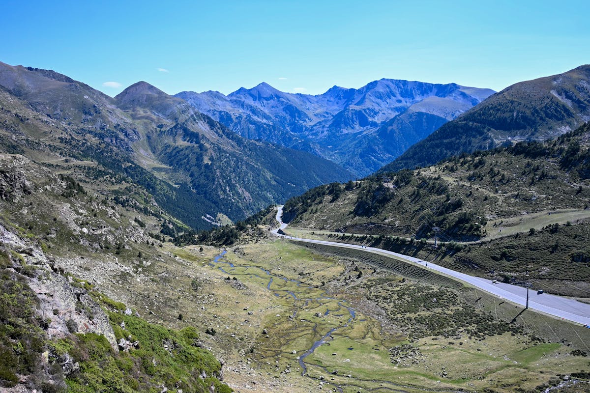 Aerial view of a winding road cutting through lush Pyrenees mountains