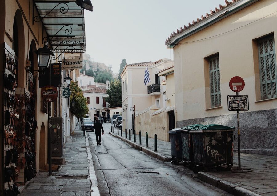 A quiet cobblestone street in the Plaka district of Athens with Greek flag