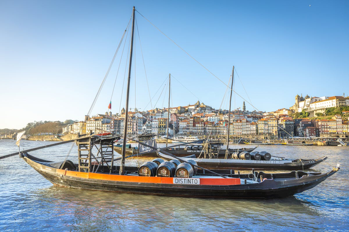 Rabelo boats with port wine barrels moored on the Douro River with Porto historic waterfront architecture behind