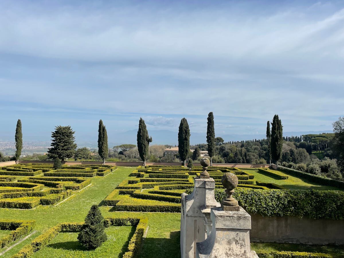 A manicured Mediterranean garden with symmetrical hedges and tall cypress trees