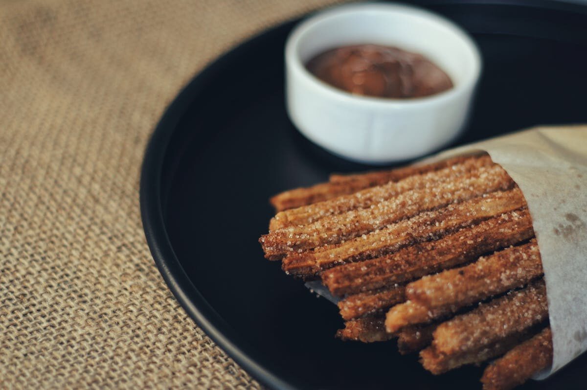 Cinnamon-dusted churros served with a bowl of thick melted chocolate dipping sauce