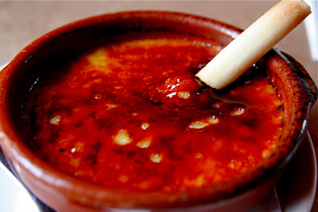 Crema catalana custard dessert with a crisp burnt sugar topping in a clay dish