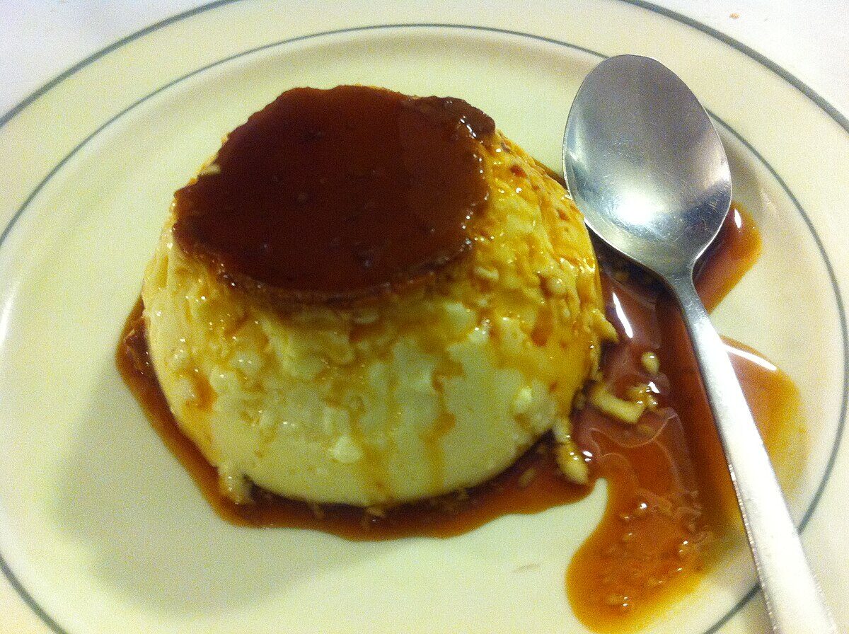 Classic Spanish flan caramel custard dessert on a white plate with golden caramel drizzle