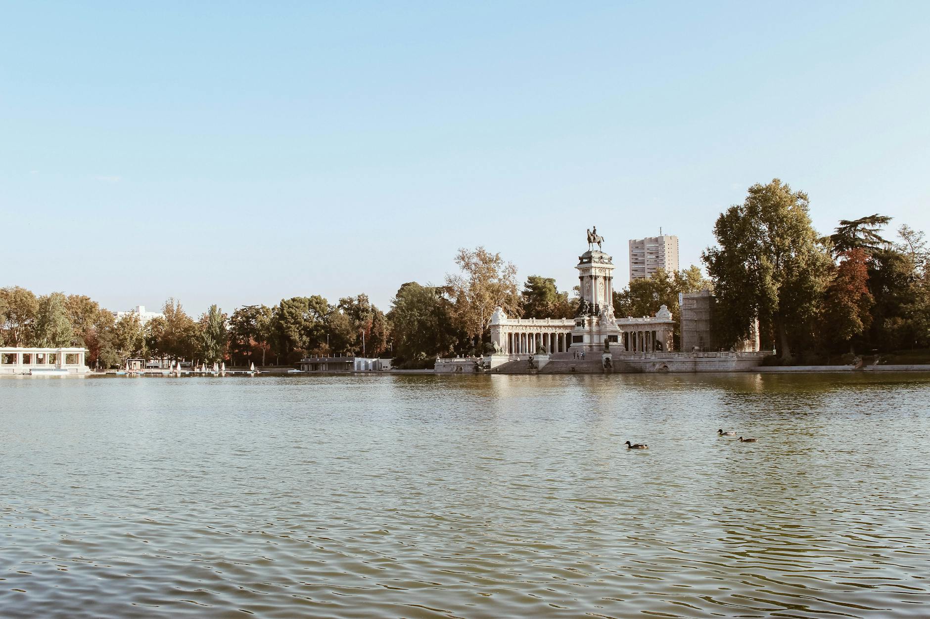 Monument and lake at El Retiro Park in Madrid, Spain, under a clear blue sky