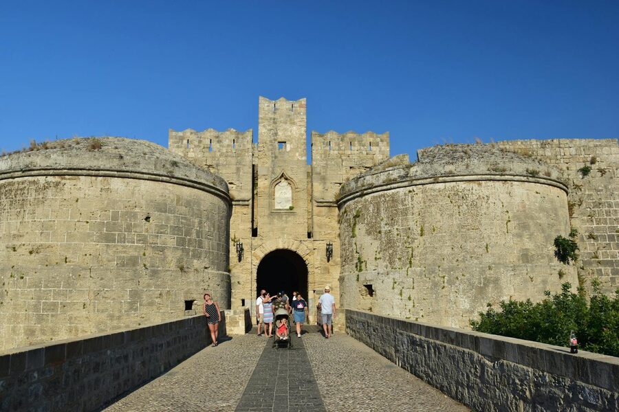 Tourists walking through a historic fortress entrance in Rhodes