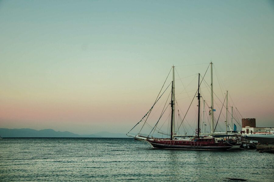 Tranquil sunset over Rhodes harbor featuring a ship
