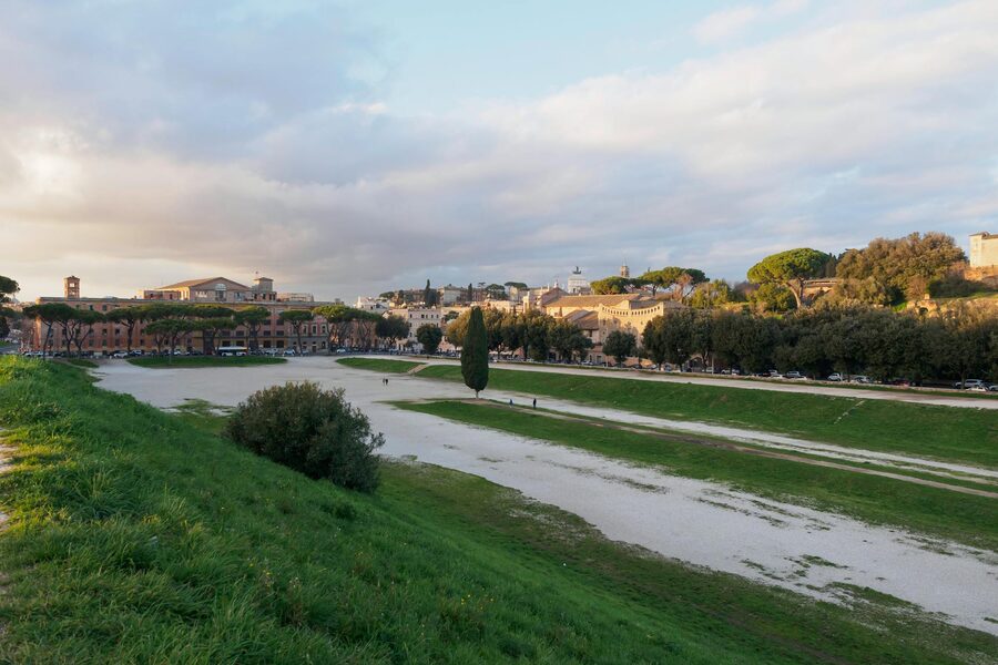 Landscape of Circus Maximus in Rome with lush greenery and a historic building in the background