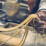 Hands making fresh pasta dough on a flour-covered surface during a cooking class in Rome