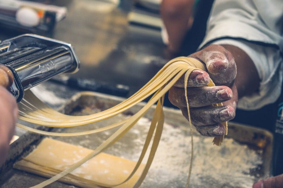 Hands making fresh pasta dough on a flour-covered surface during a cooking class in Rome