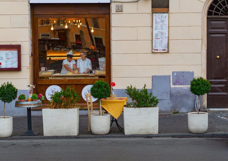 Street view of an Italian bakery with chefs preparing pizza inside, Rome