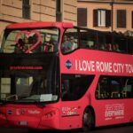 Double-decker open-top sightseeing bus driving through Rome with tourists on the upper deck