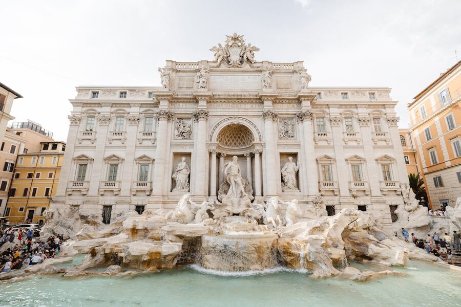 The Trevi Fountain in Rome on a sunny day with visitors gathered around
