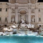 The Trevi Fountain lit up at night with Baroque sculptures and flowing water in Rome