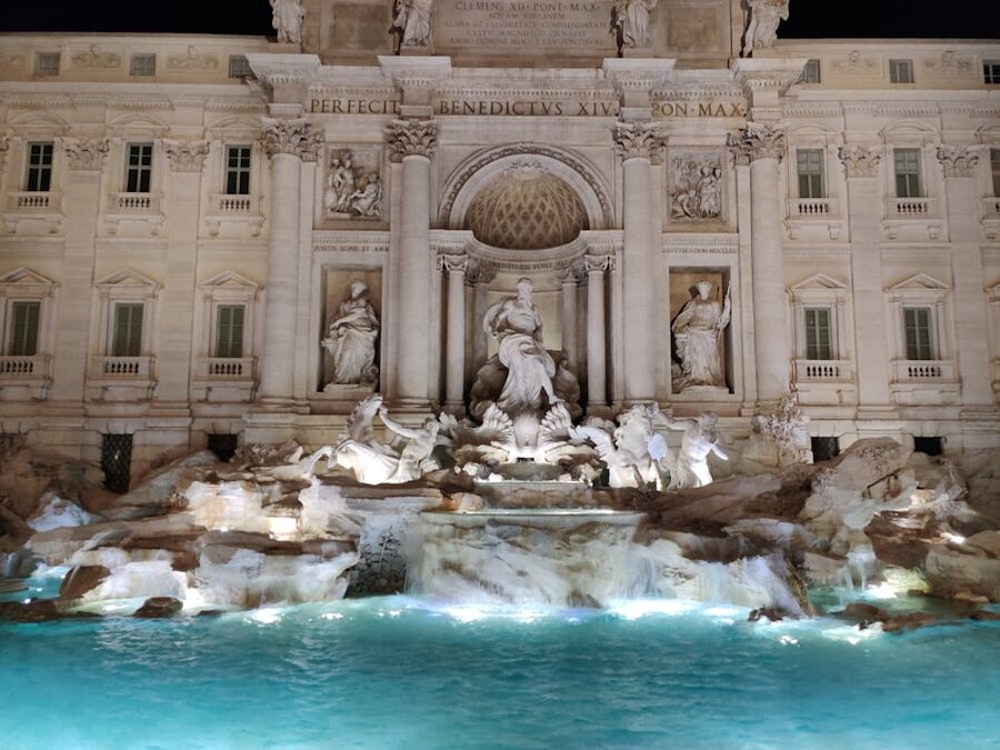 The Trevi Fountain lit up at night with Baroque sculptures and flowing water in Rome