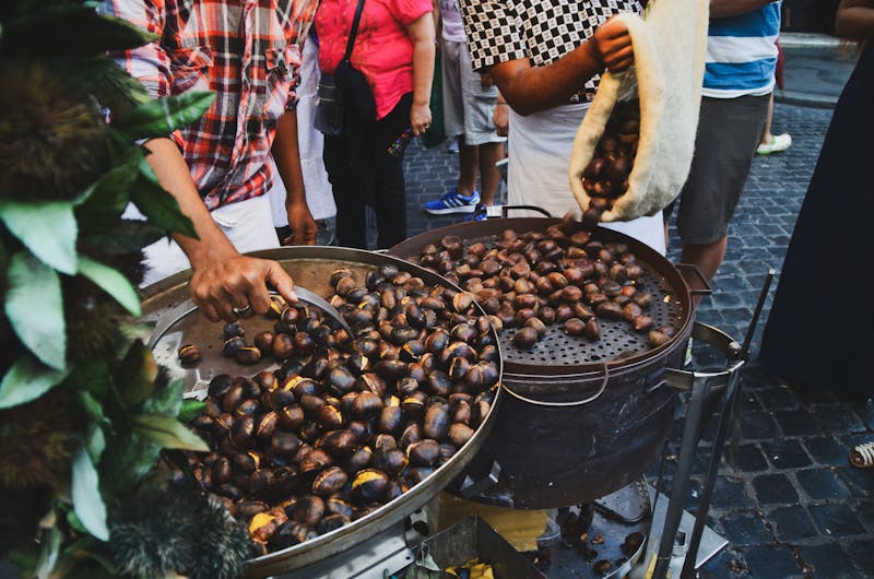 Street vendor roasting chestnuts over open fire at a Rome market