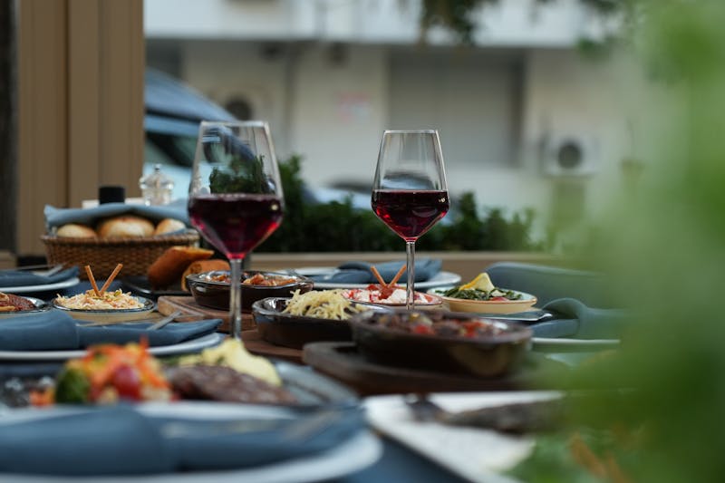 Outdoor table setting with red wine and gourmet dishes
