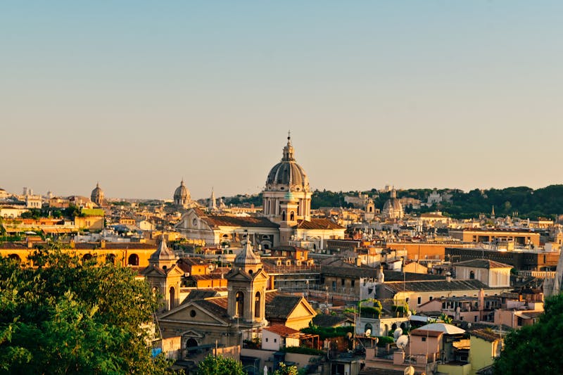 Rome skyline at sunset with church domes and historic buildings silhouetted against the sky