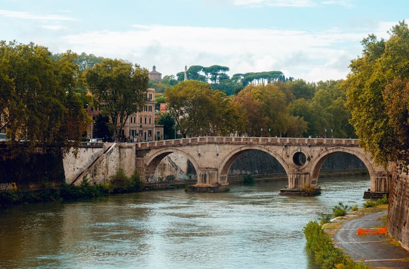 View across the Tiber River toward St Peter's Basilica dome with a bridge in the foreground