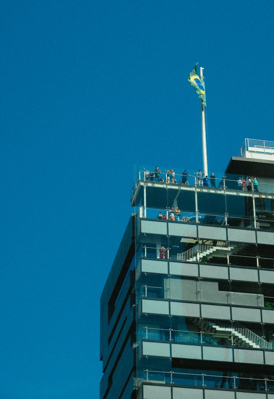People on a building rooftop viewing deck enjoying a city panorama under clear blue sky
