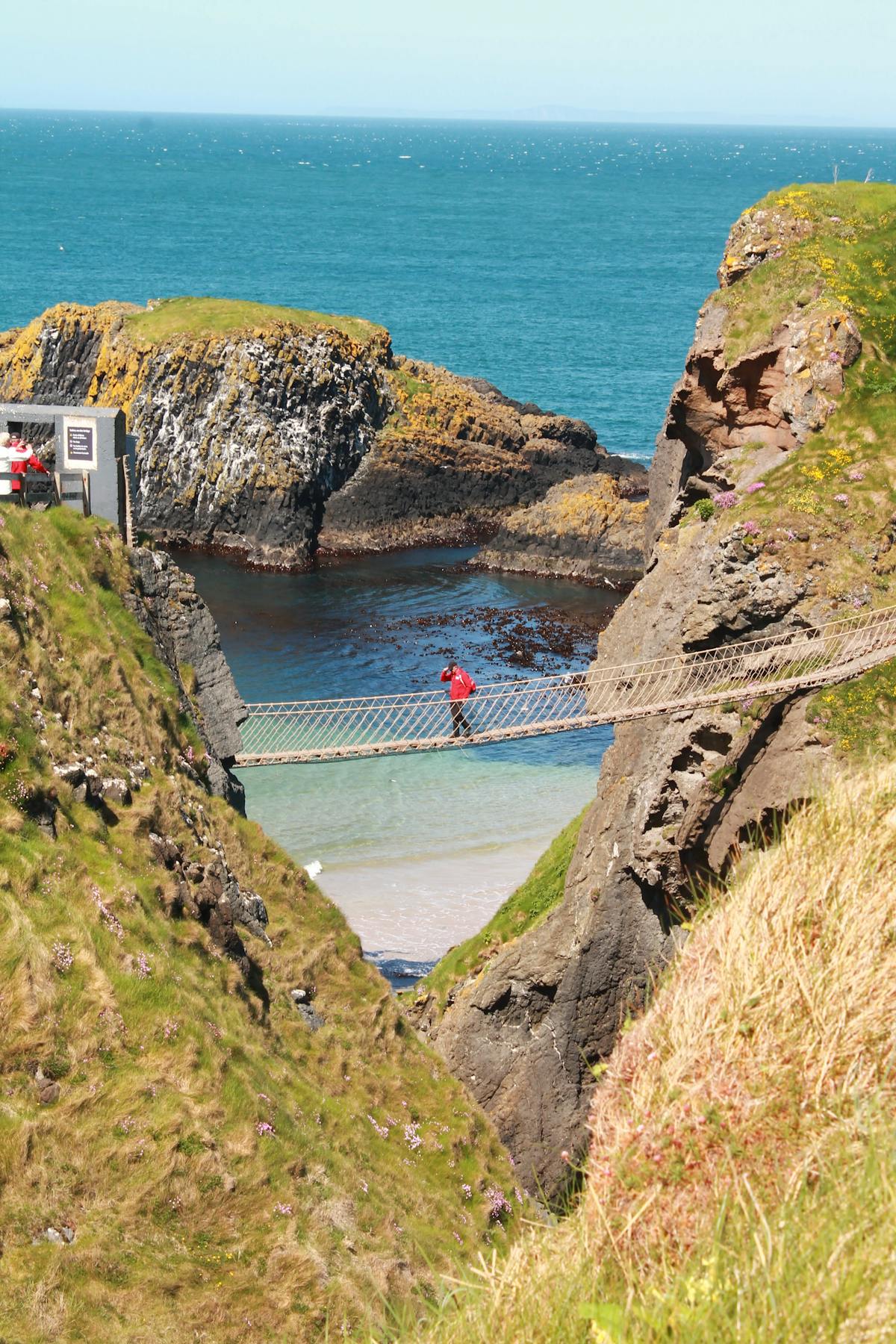 Person walking across the Carrick-a-Rede Rope Bridge in Northern Ireland