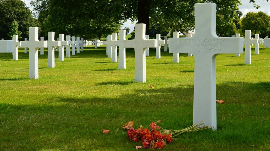 Rows of white crosses in a World War II cemetery under clear skies