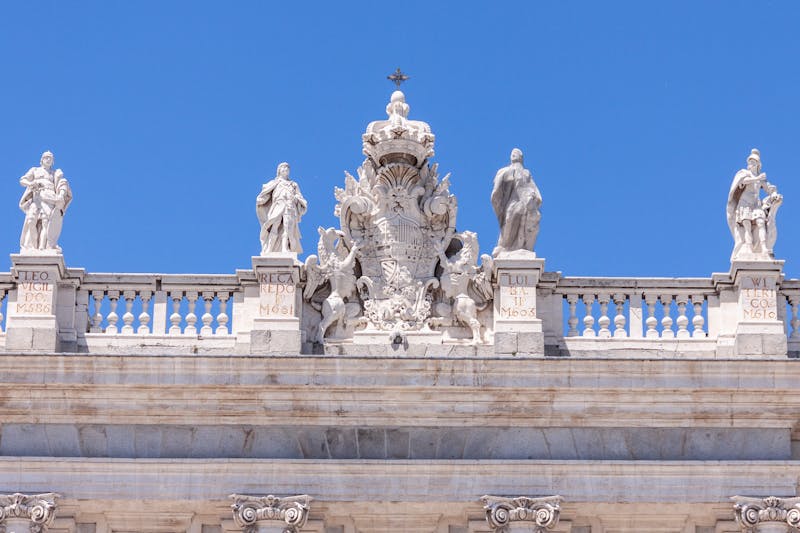 Detailed stone sculptures along the roofline of the Royal Palace of Madrid