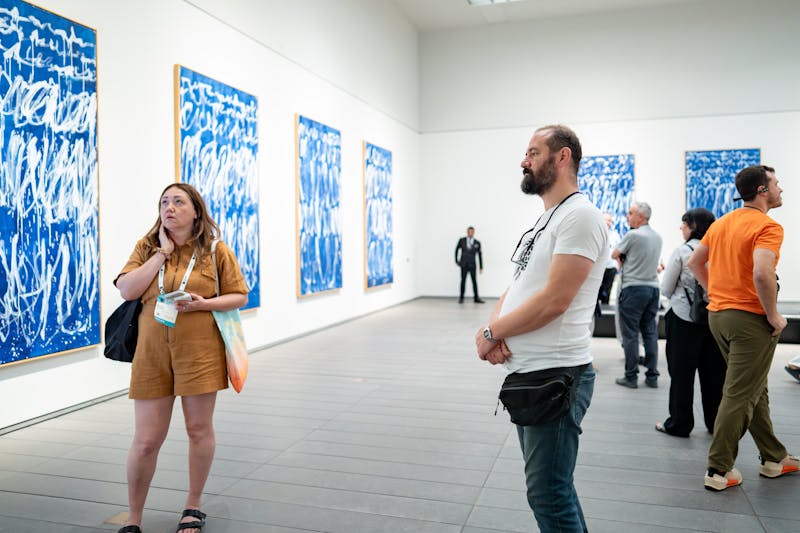 Museum visitors engaging with blue abstract artworks in a contemporary gallery space