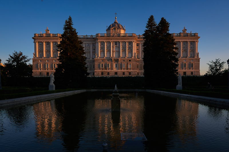 The Royal Palace of Madrid reflected in the Sabatini Gardens pool at dusk