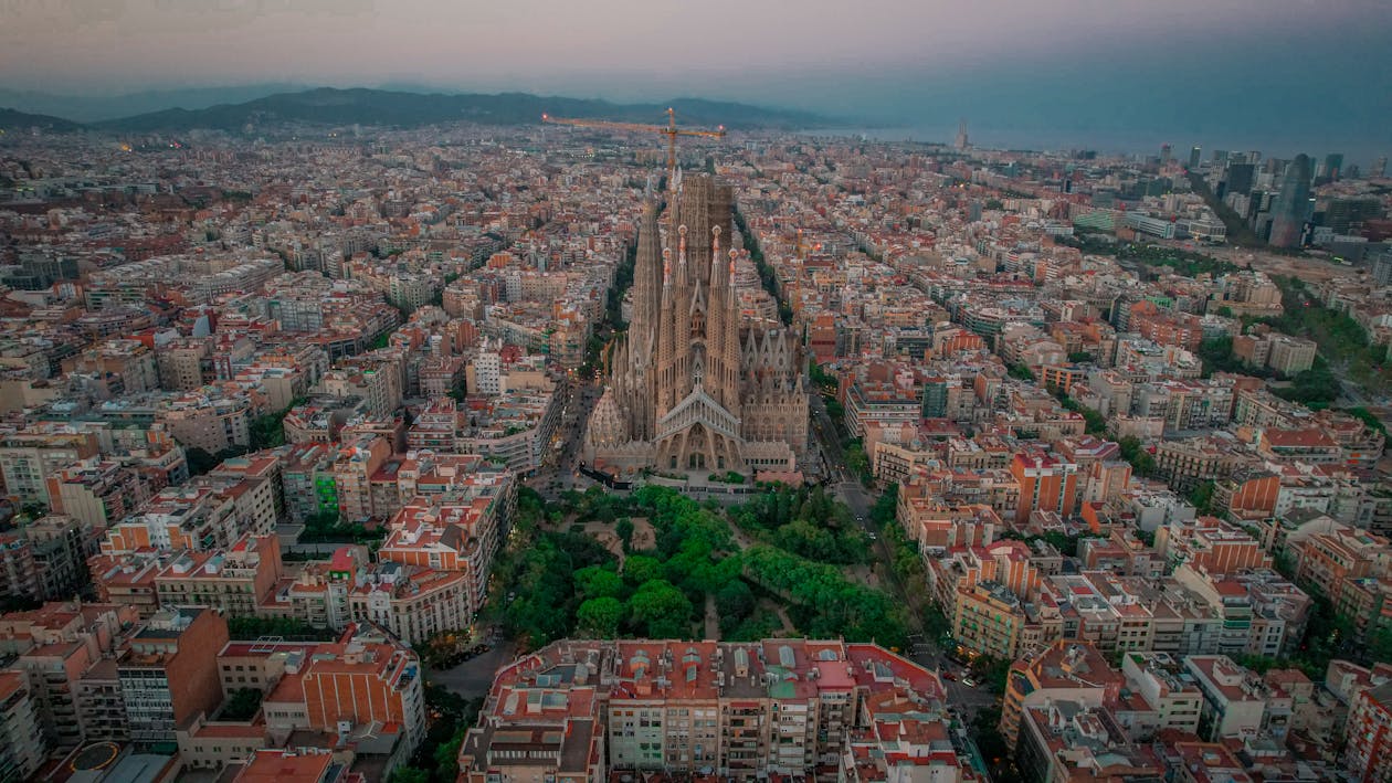 Aerial view of Sagrada Familia at twilight with Barcelona city surrounding it