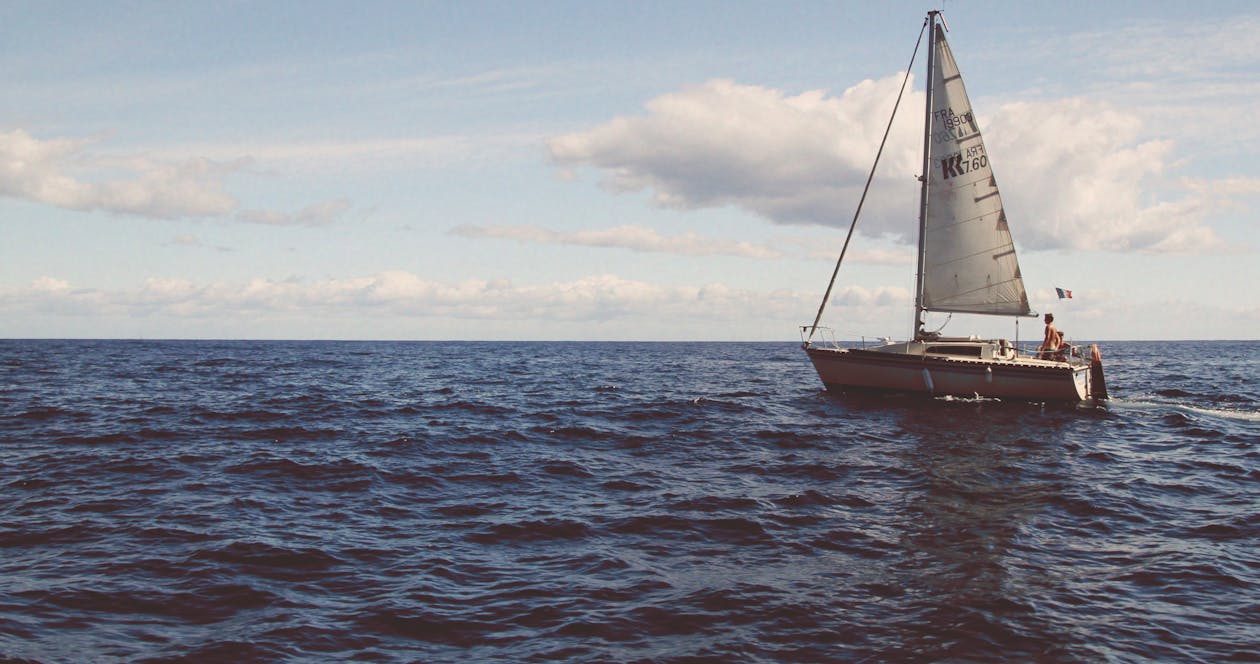 A sailboat sailing across the open Mediterranean sea under a clear sky