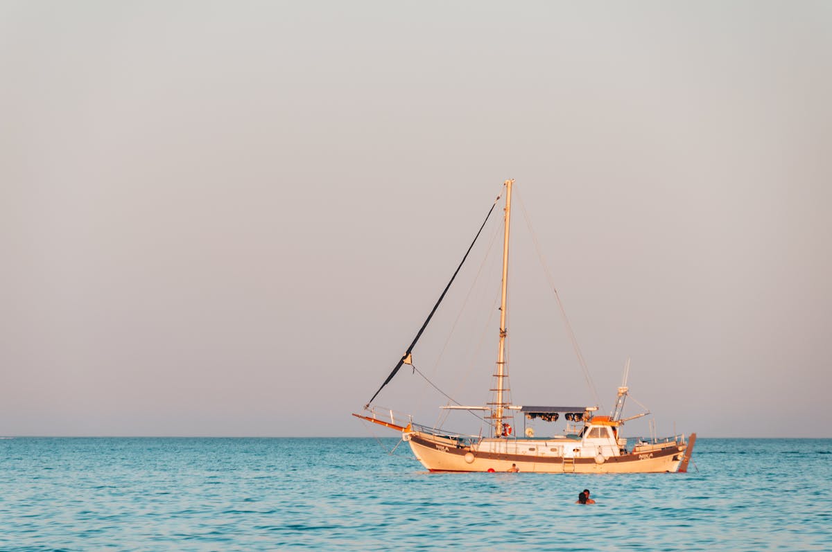 Sailboat floating on calm ocean waters at sunset