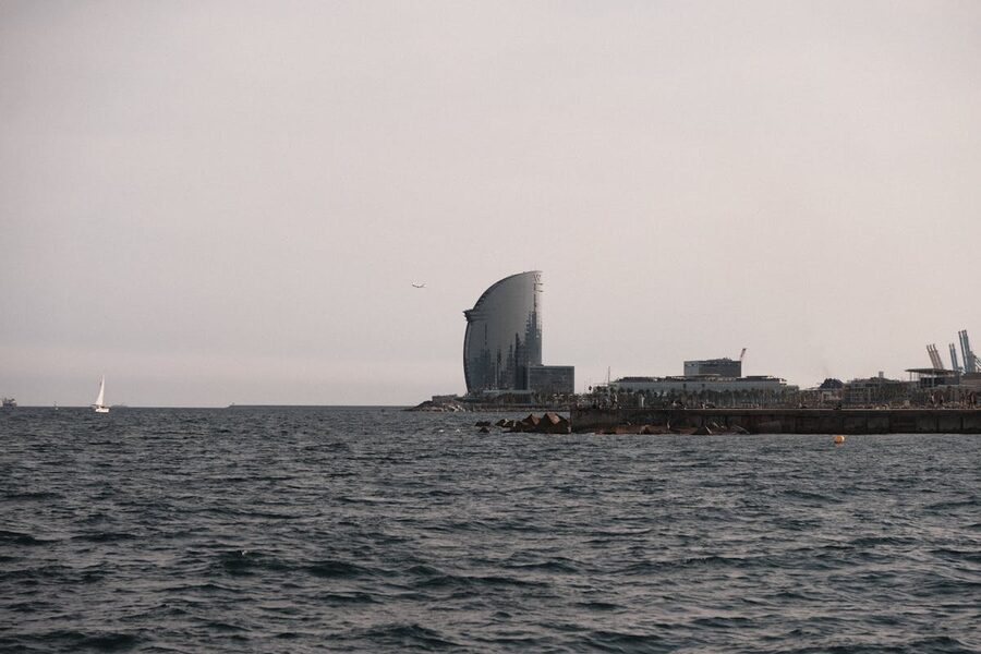 Serene view of sailboat near W Hotel in Barcelona under warm sunset
