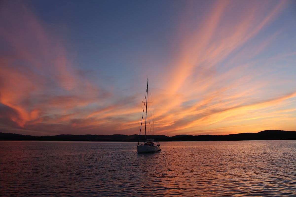 Sailboat silhouetted against a vibrant sunset over the Mediterranean sea
