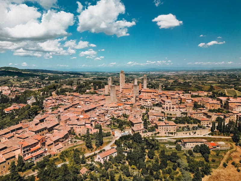 Aerial photograph of San Gimignano medieval town with towers surrounded by green Tuscan hills