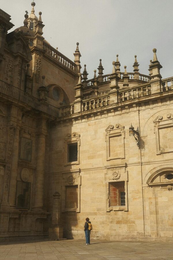A person standing before the ornate facade of Santiago de Compostela Cathedral