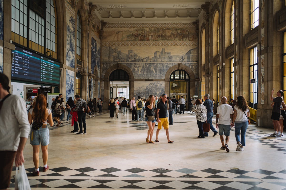 Interior of Sao Bento train station in Porto showing the grand hall with azulejo tile murals and visitors