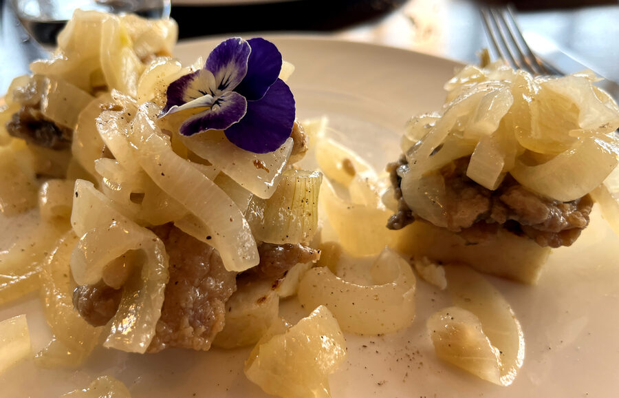 A plate of sarde in saor showing sardines with sweet and sour onions and pine nuts