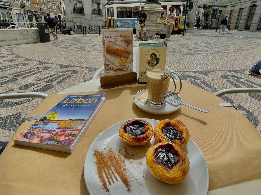 Pasteis de nata with coffee at a traditional Lisbon cafe with an iconic yellow tram passing outside