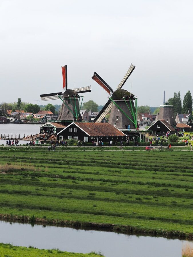 Iconic Dutch windmills along a green riverbank at Zaanse Schans in the Netherlands