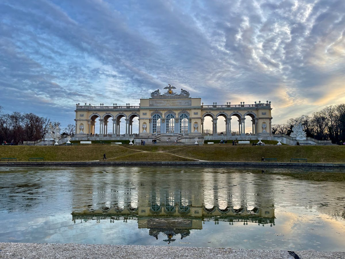 The Gloriette building reflected in water at sunrise at Schonbrunn Vienna