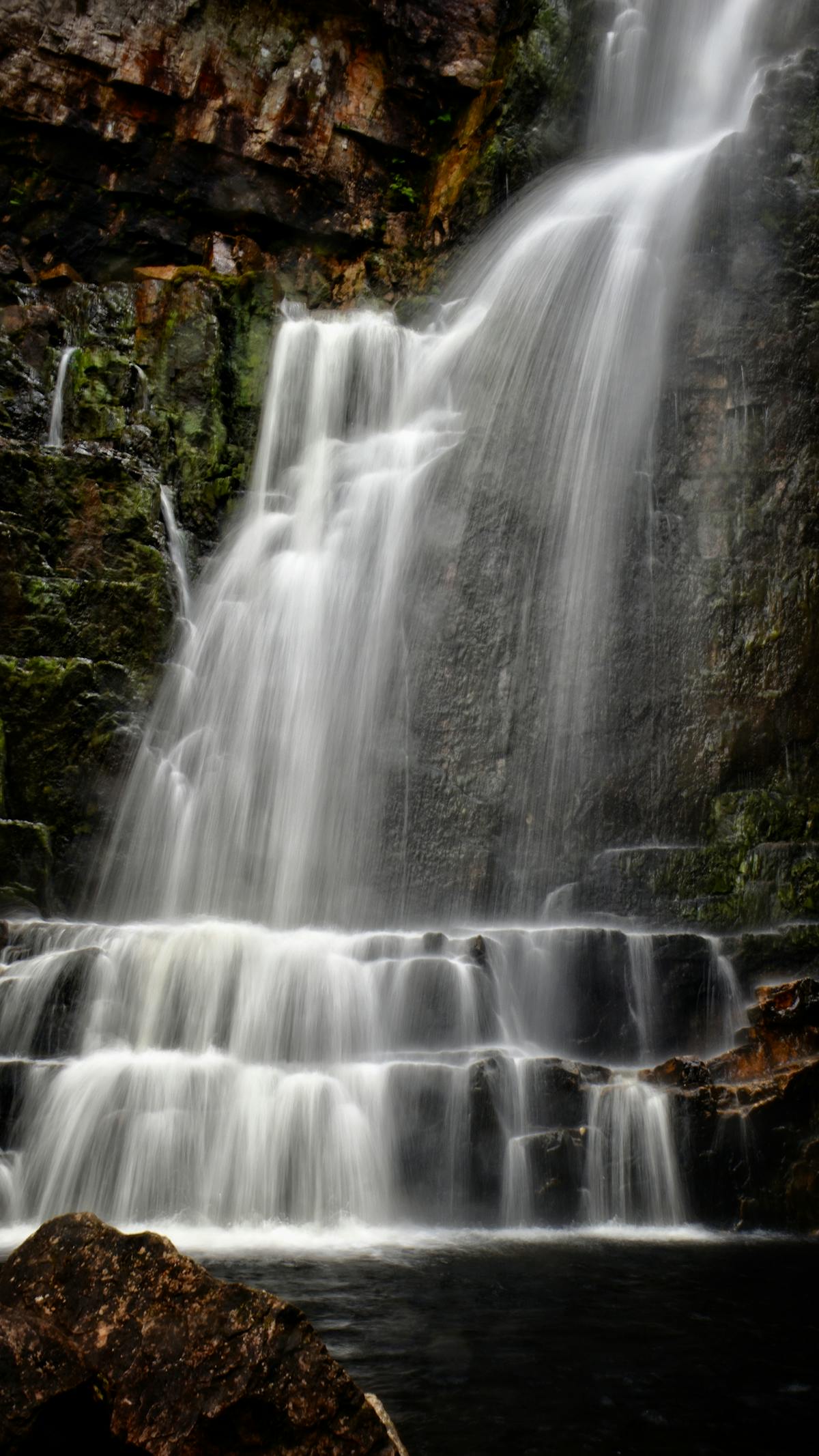 A waterfall cascading down moss-covered rocks in the Scottish Highlands