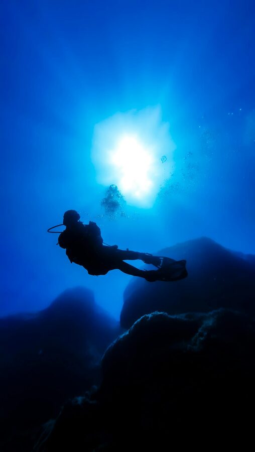 Silhouette of a scuba diver swimming through sunlit Mediterranean waters