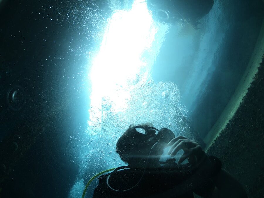 Scuba diver exploring underwater with sunlight streaming through the water above