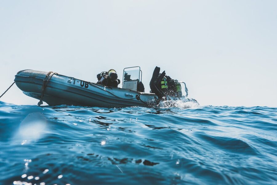 Scuba divers equipped for a dive preparing from an inflatable boat on a sunny day