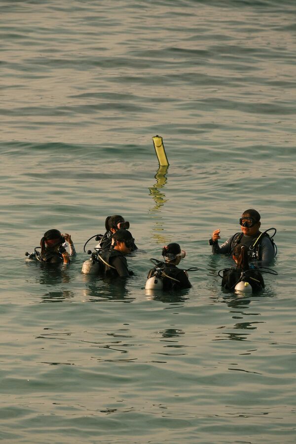 Scuba divers preparing for a dive in the ocean focusing on teamwork and safety