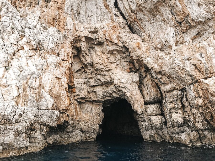 Entrance to a sea cave with crystal turquoise water and limestone walls