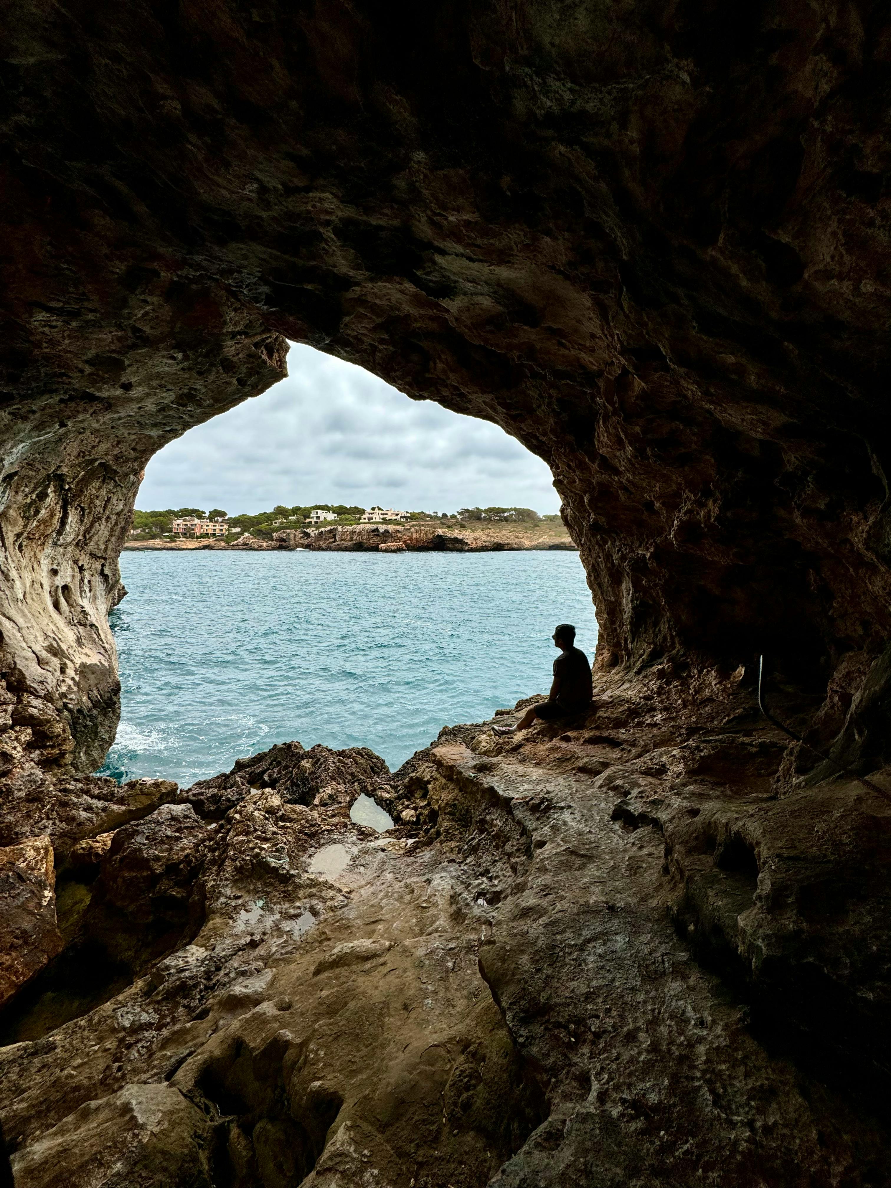 Silhouette inside a sea cave overlooking the blue Mediterranean waters