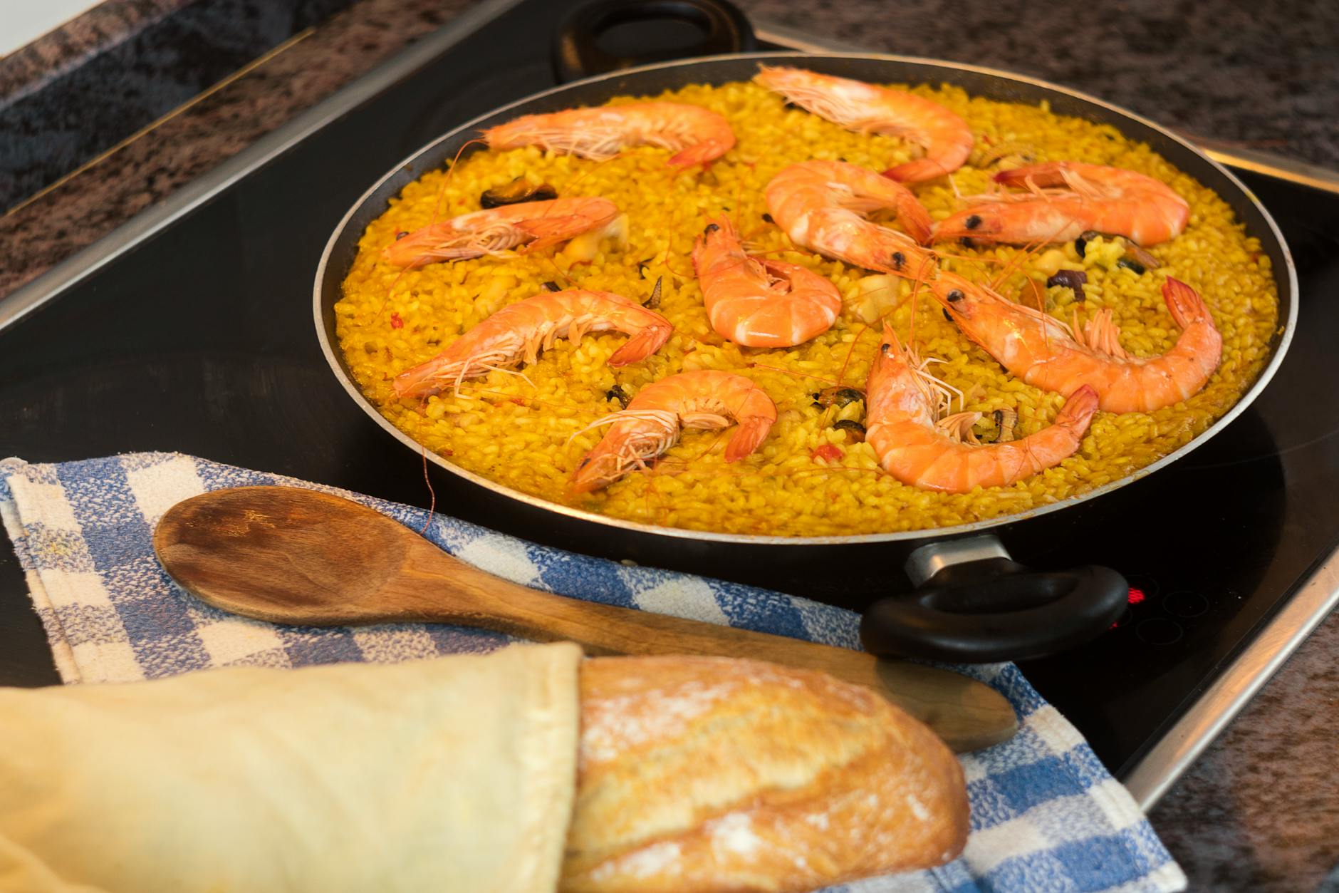 A seafood paella with prawns cooking on a stovetop