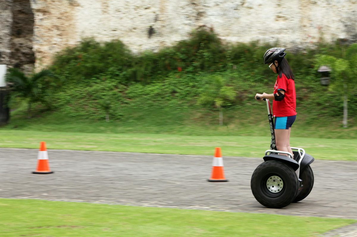 Young girl riding a Segway outdoors wearing safety helmet