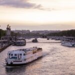 Golden sunset over the Pont Alexandre III bridge with cruise boats on the Seine River in Paris